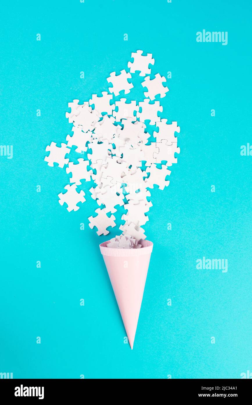Cone with white puzzle pieces, blue background, spreading the jigsaw ...