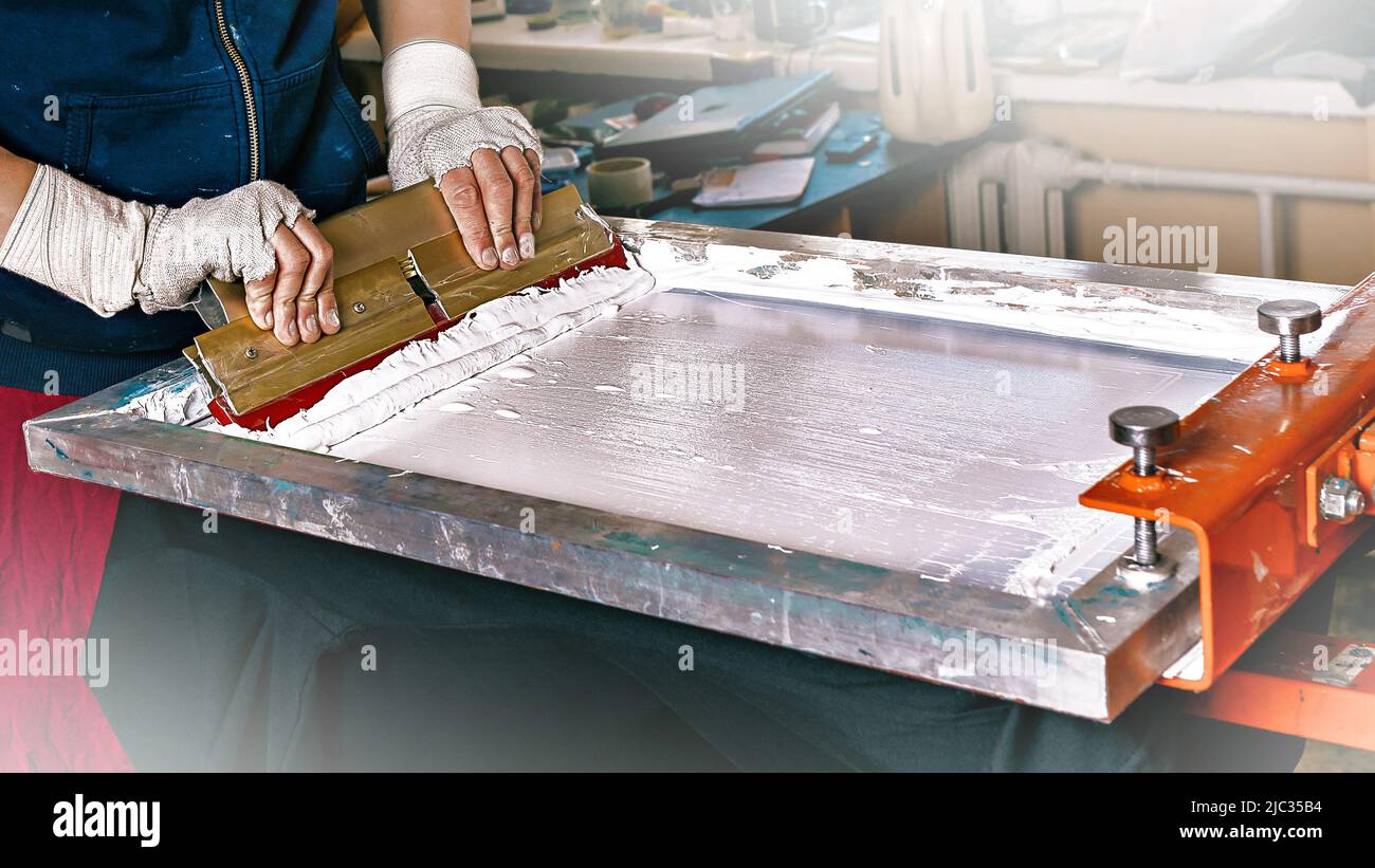 silk screen textile printery. male hand with a squeegee. creating print ...
