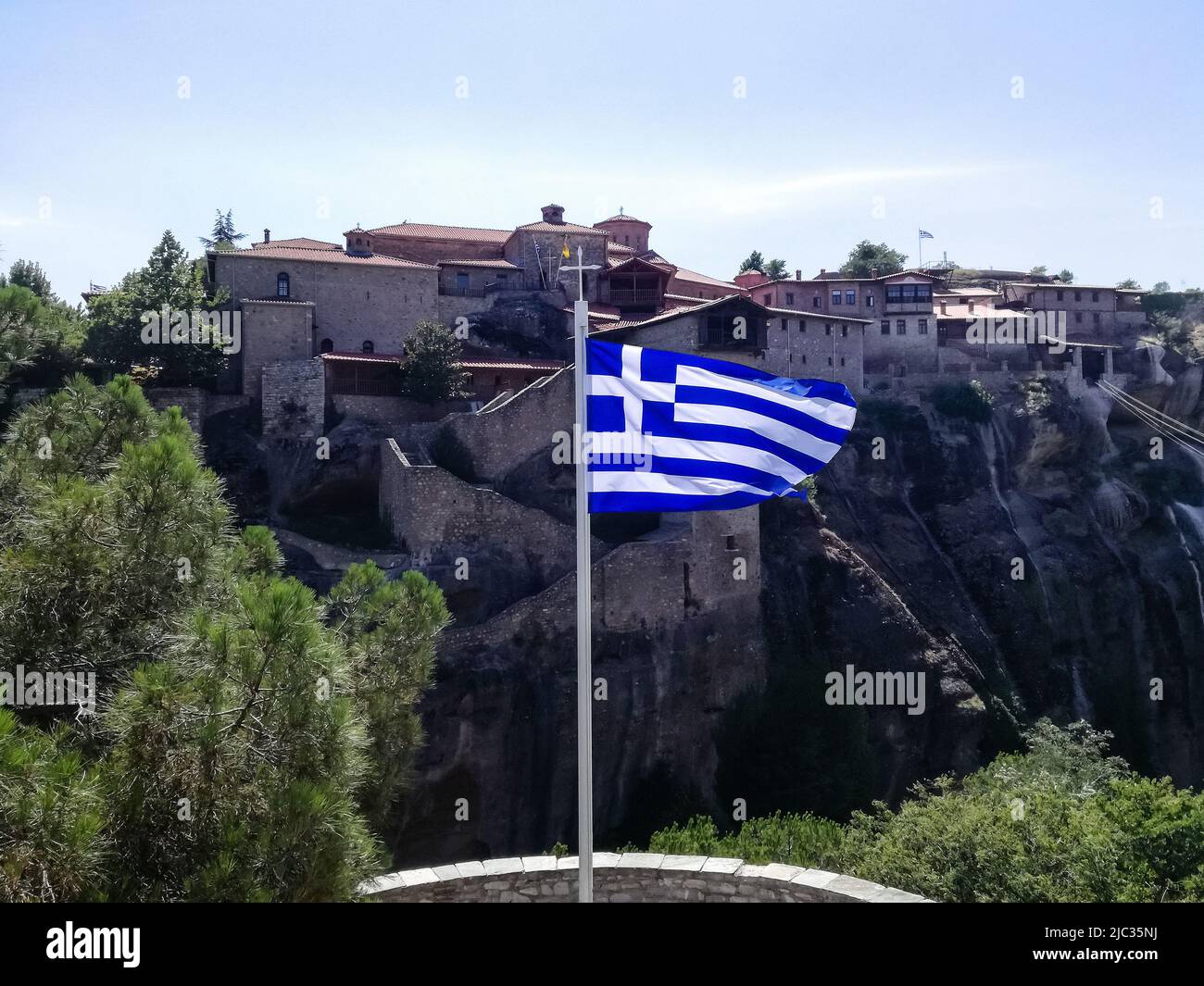 Flag of Greece is displayed against background of ancient monastery ...