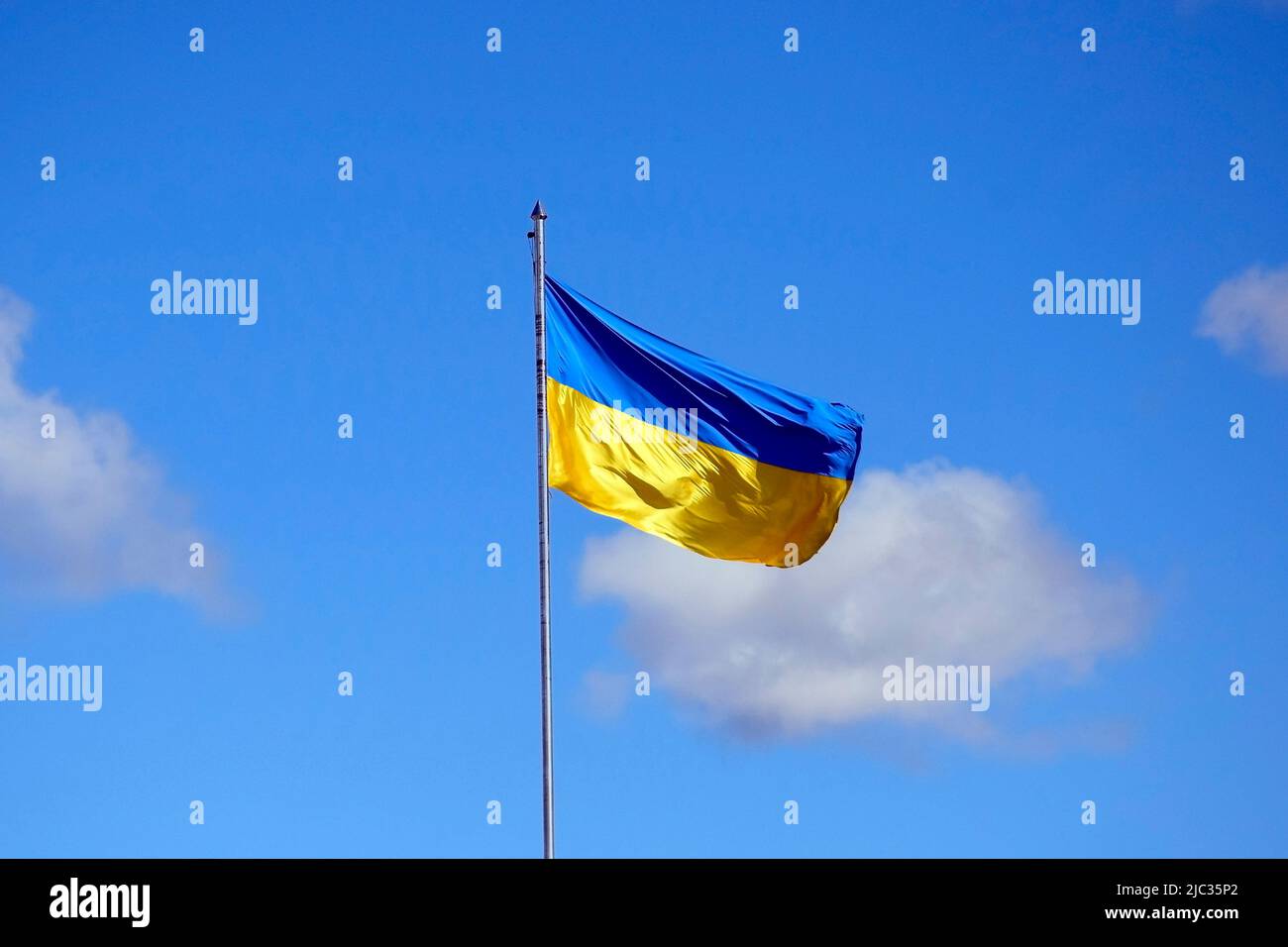 Ukrainian flag on flagpole against the blue cloudless sky. The official ...