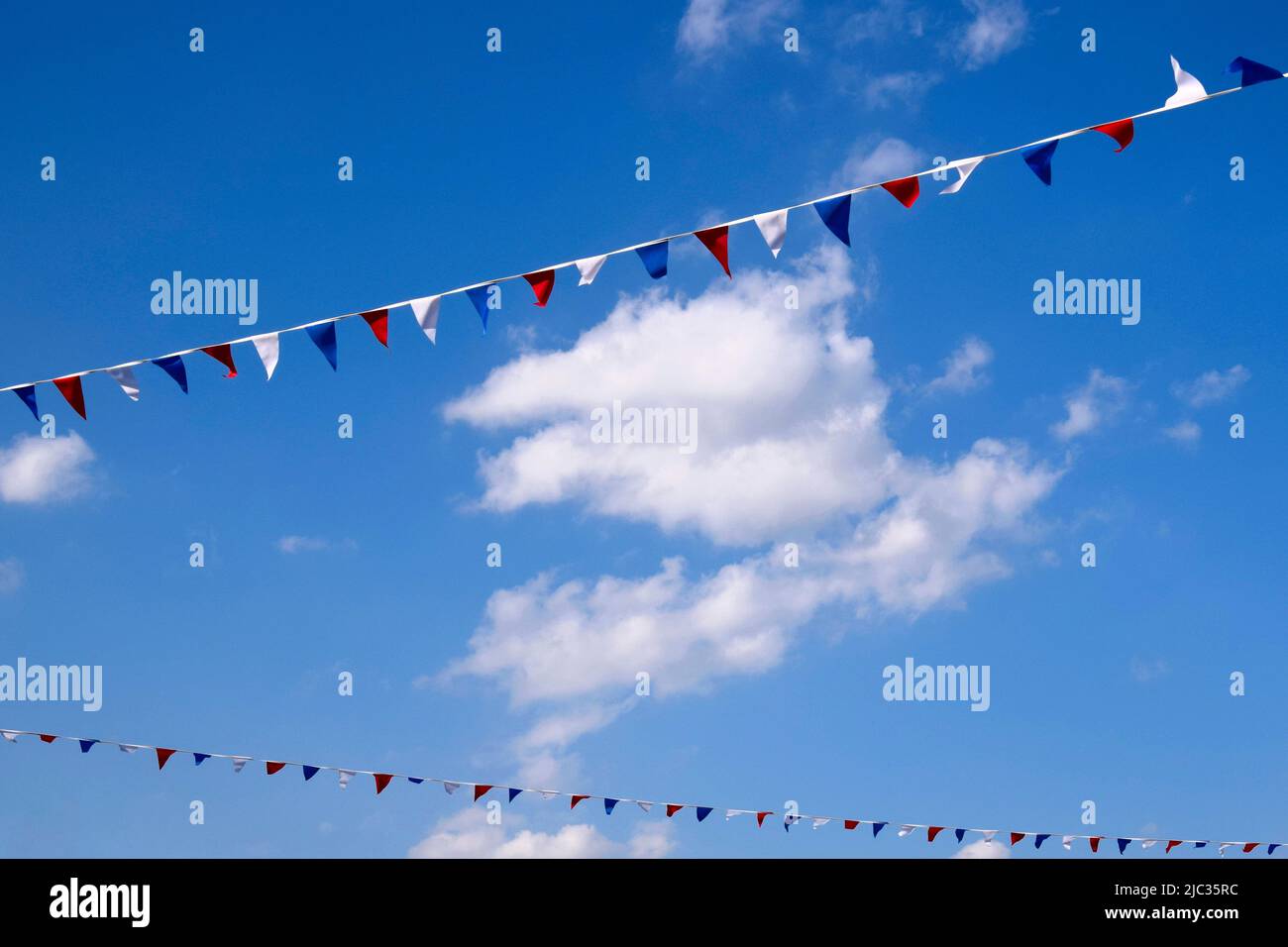 Colourful decorative triangular flags under blue sky with clouds. Sunny ...