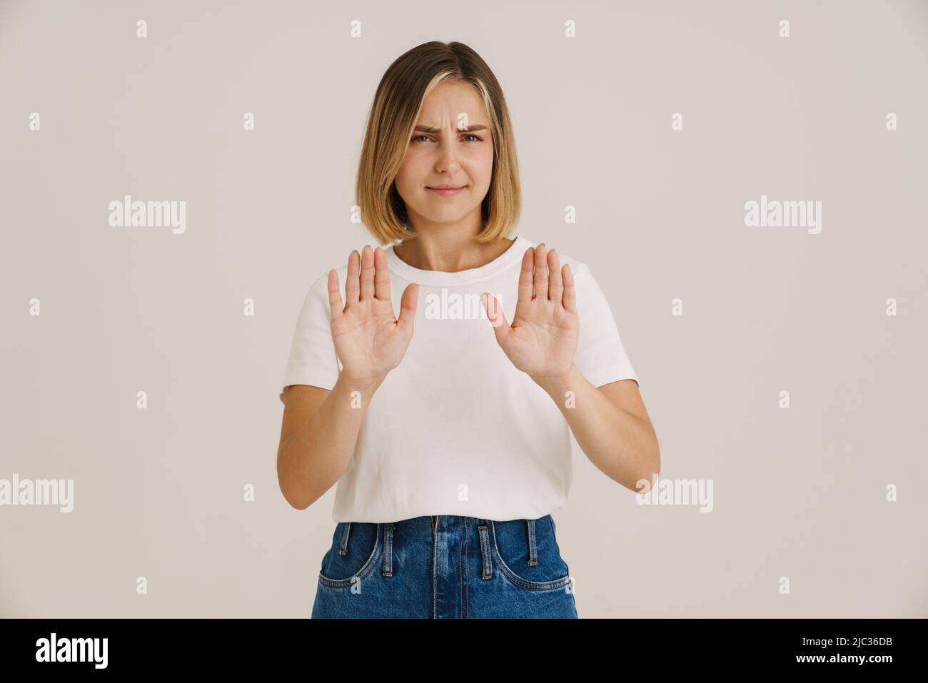 Young blonde woman frowning while showing stop gesture isolated over ...