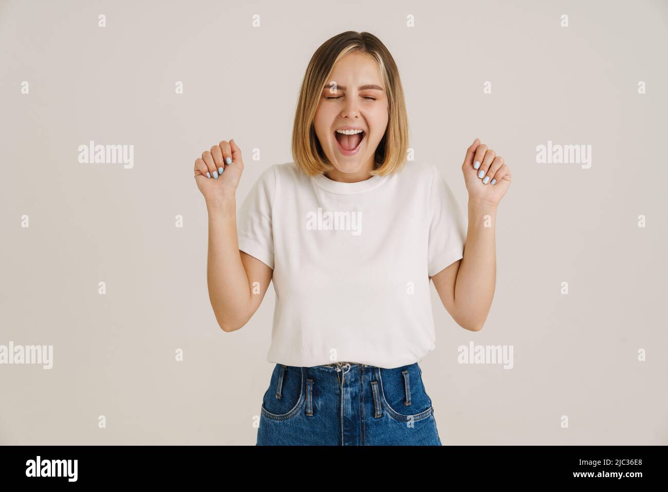 Young blonde woman screaming while making winner gesture isolated over ...