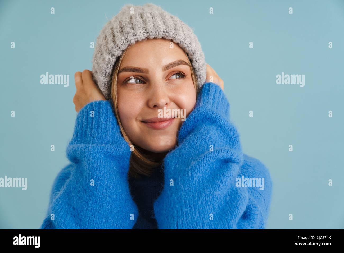 Young blonde woman wearing knit hat smiling at camera isolated over ...