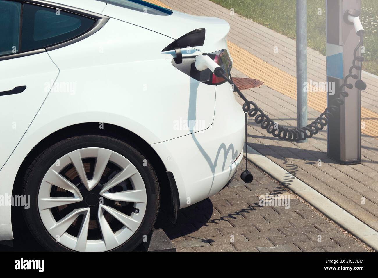 Close up of power supply plugged into gray electric car being charged ...
