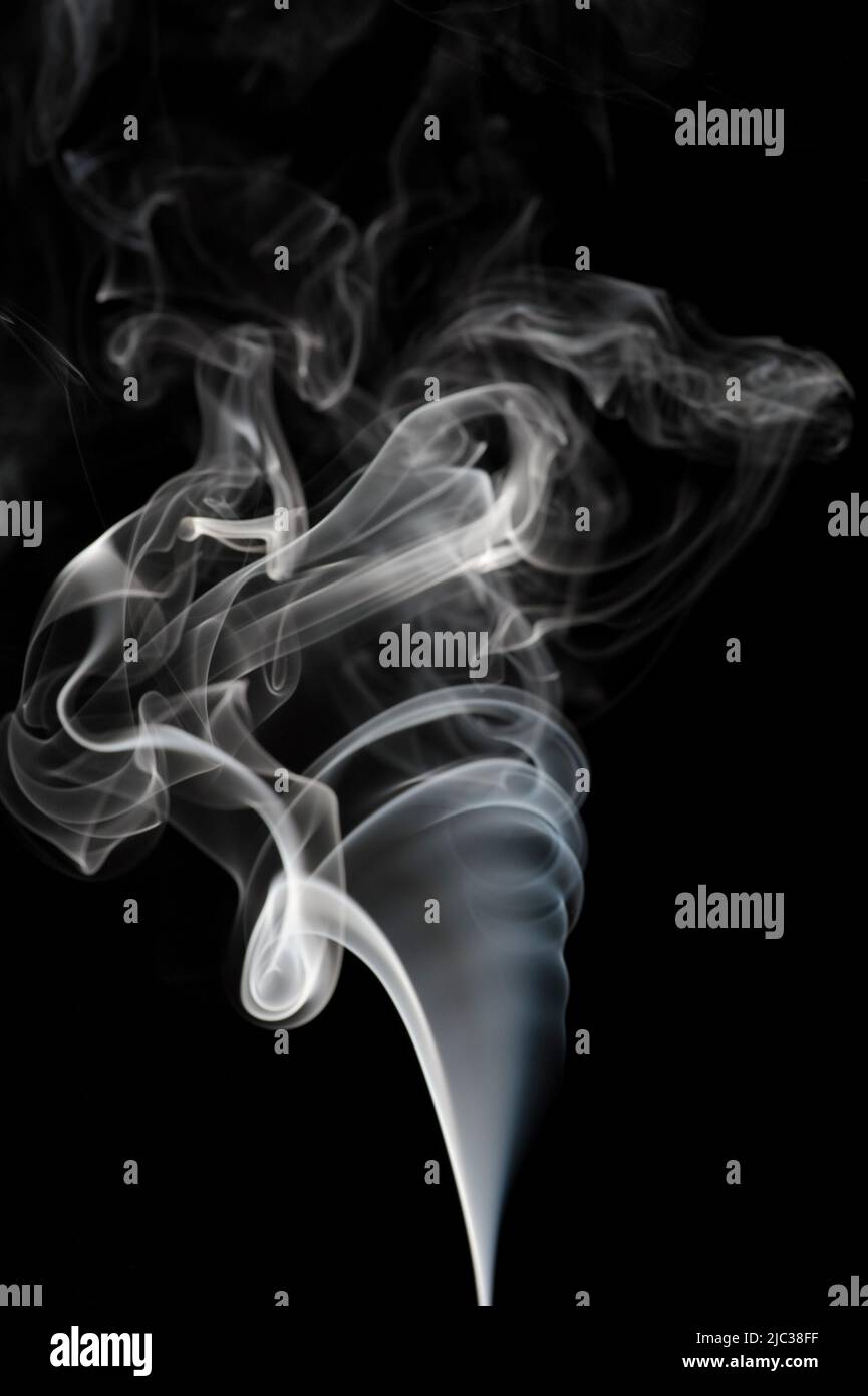 Puffs and curls of white smoke against a black background rising from a ...