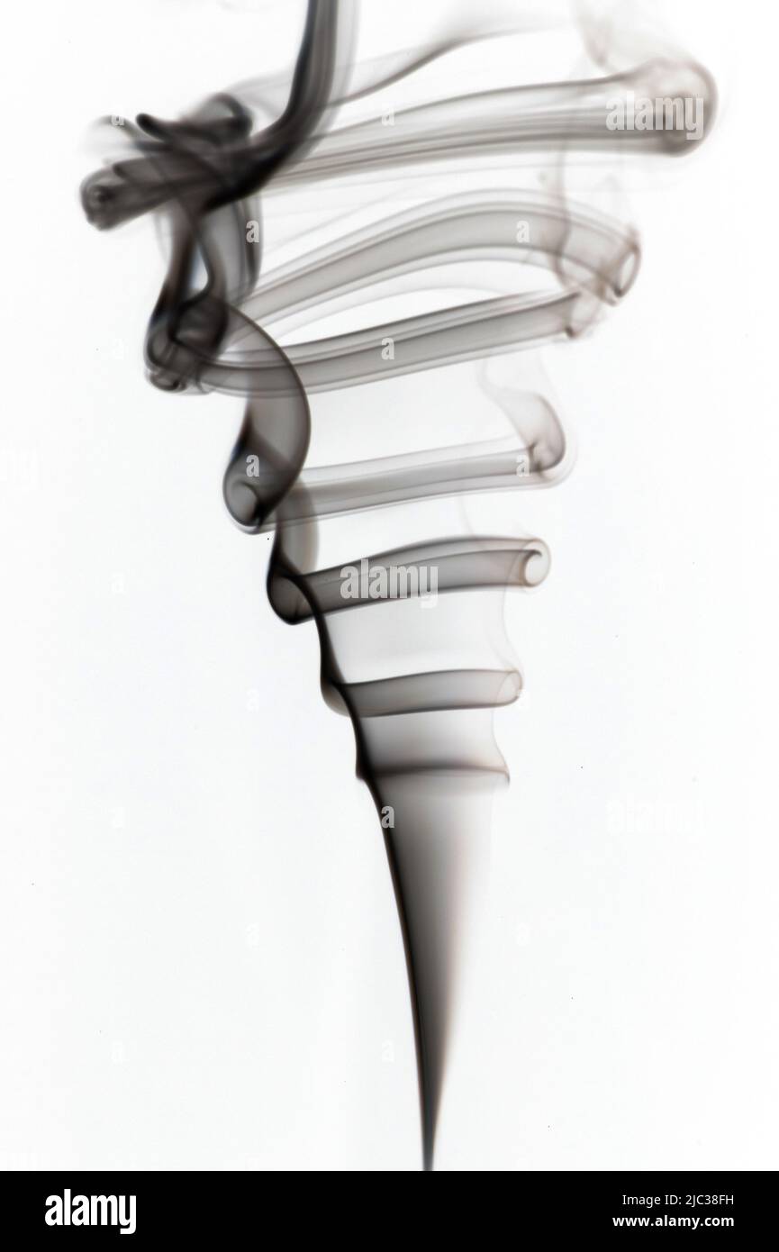 Puffs and curls of dark smoke on a white background rising from a ...