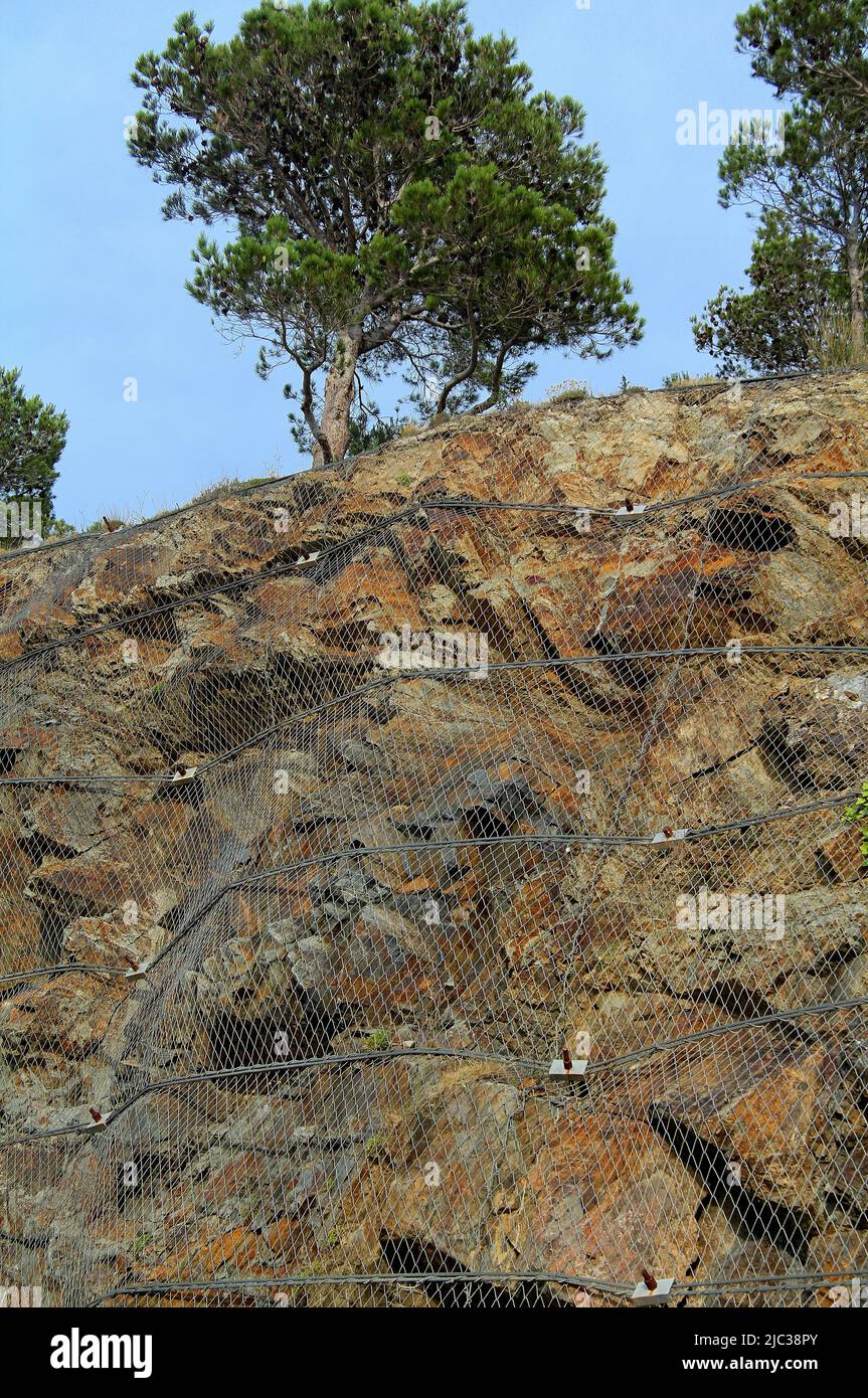 Draped mesh rockfall barrier along Stock Photo - Alamy