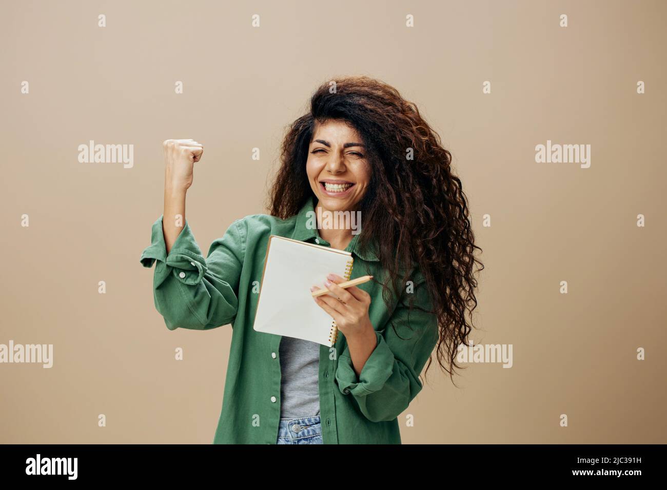 SUCCESS CONCEPT. Overjoyed tanned curly Latin female in casual things ...