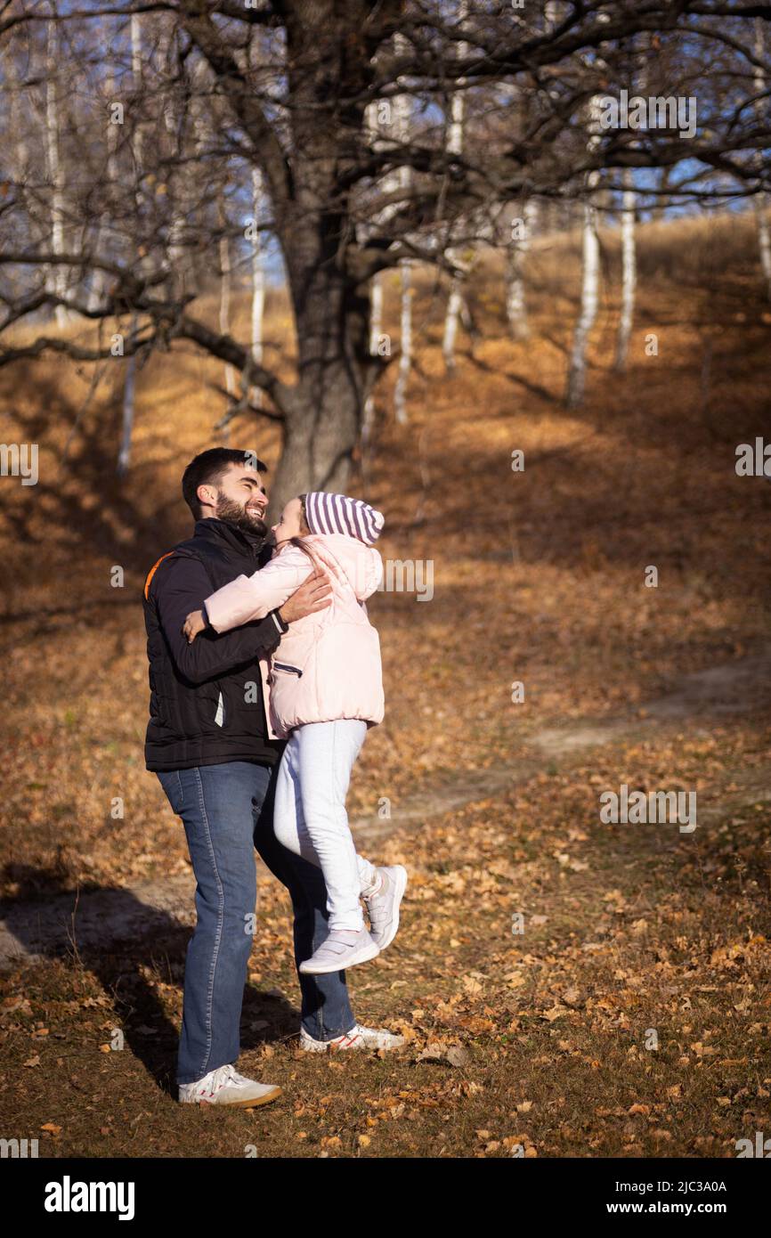 Father raising young daughter in arms both smiling and having fun on a ...