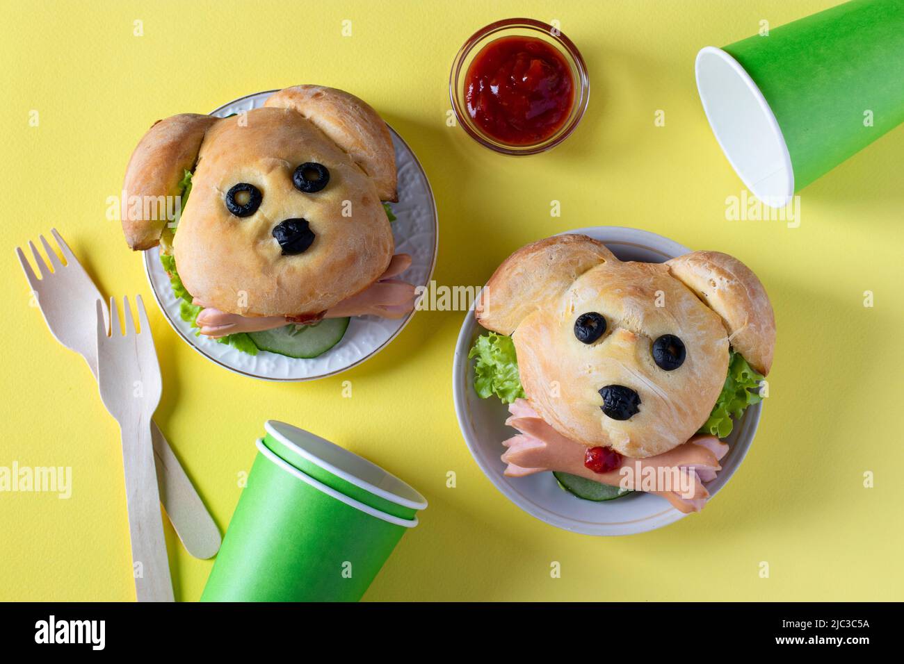 Sandwiches in the shape of dog with a sausage on yellow background ...