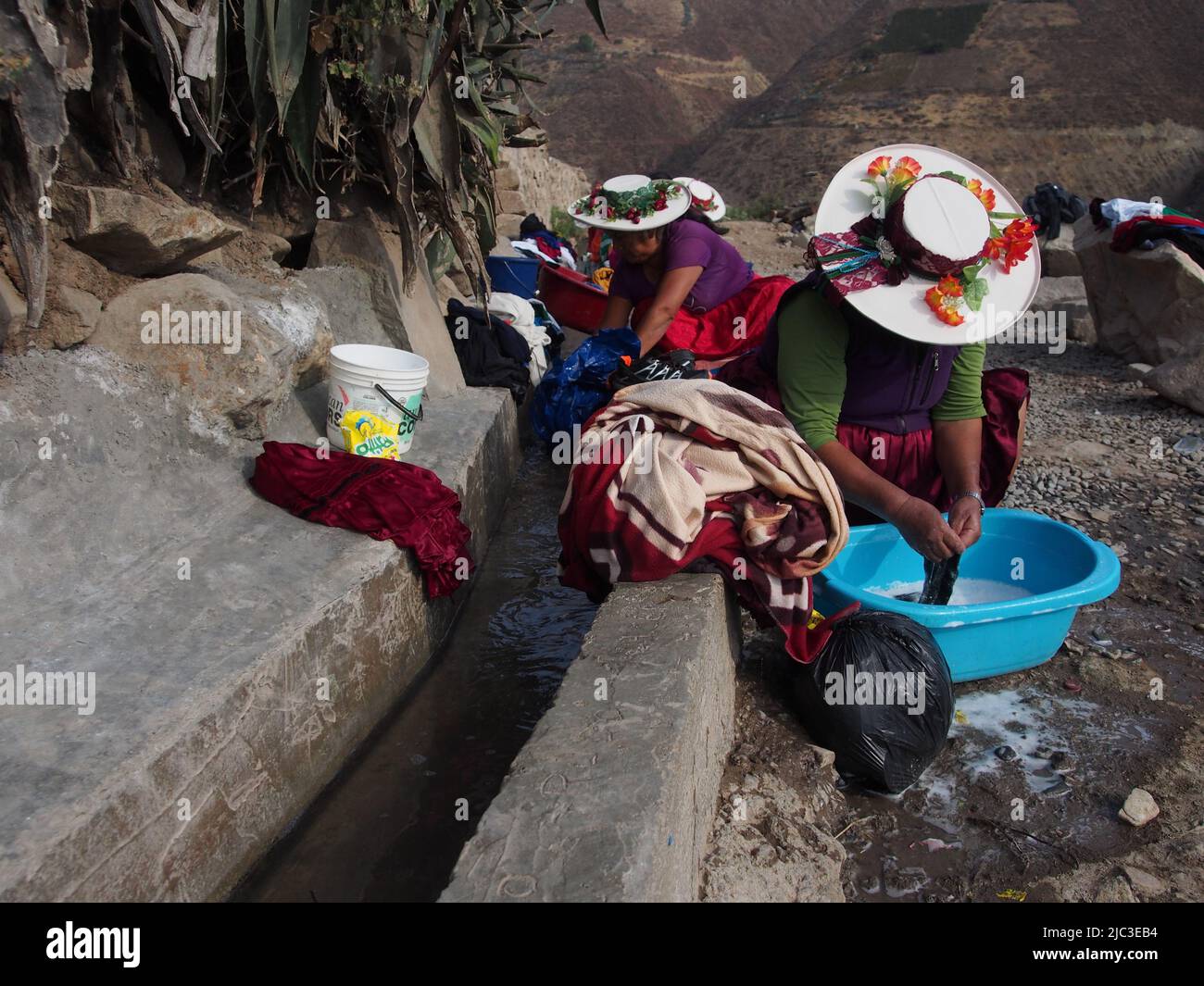 Group of indigenous andean women washing clothes in a ditch in the ...