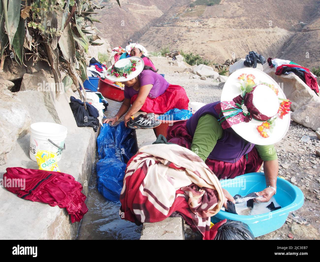 Group of indigenous andean women washing clothes in a ditch in the ...