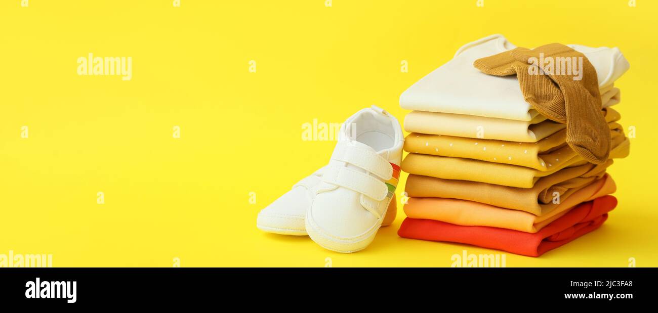 Set of stylish baby clothes on yellow background with space for text ...