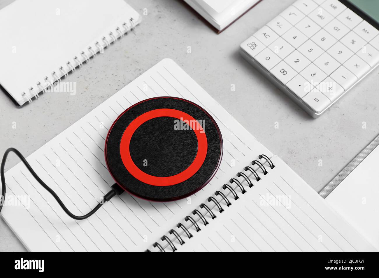 Wireless charger pad, notebooks and calculator on light background ...