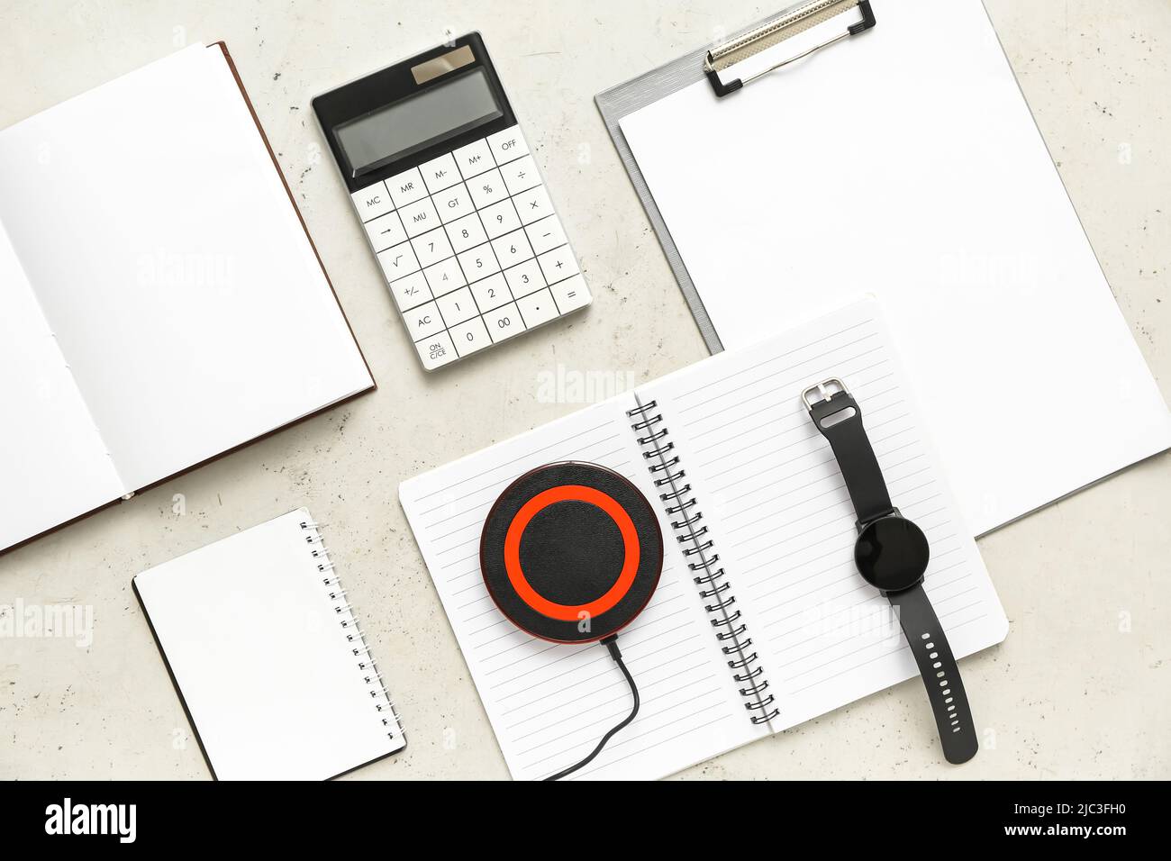 Wireless charger pad, smartwatch, calculator and notebooks on light ...