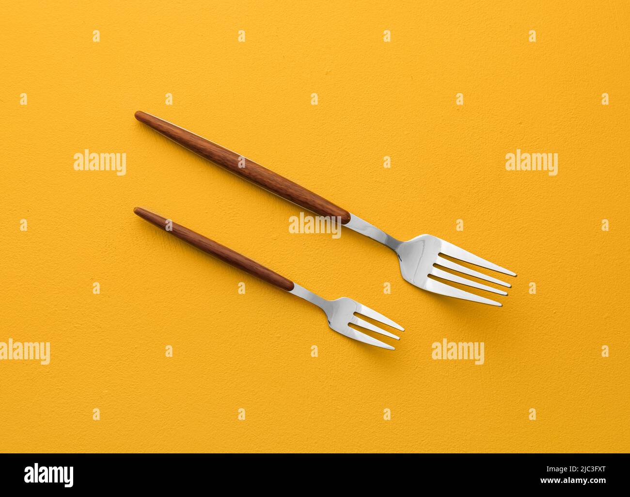 Stylish stainless steel forks on yellow background Stock Photo - Alamy