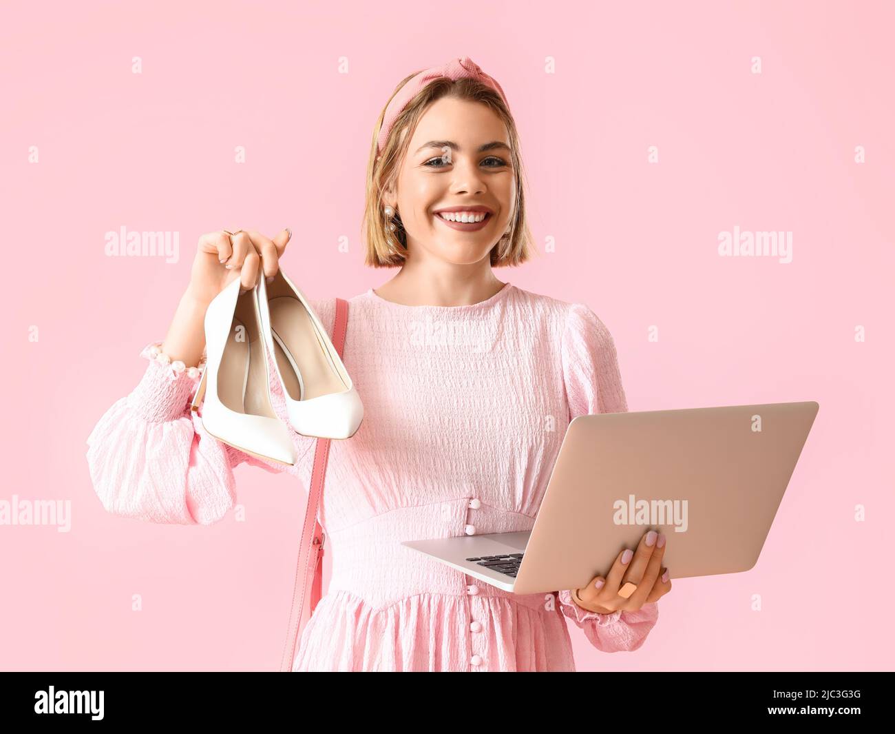 Young woman with laptop and new heels on pink background. Online ...
