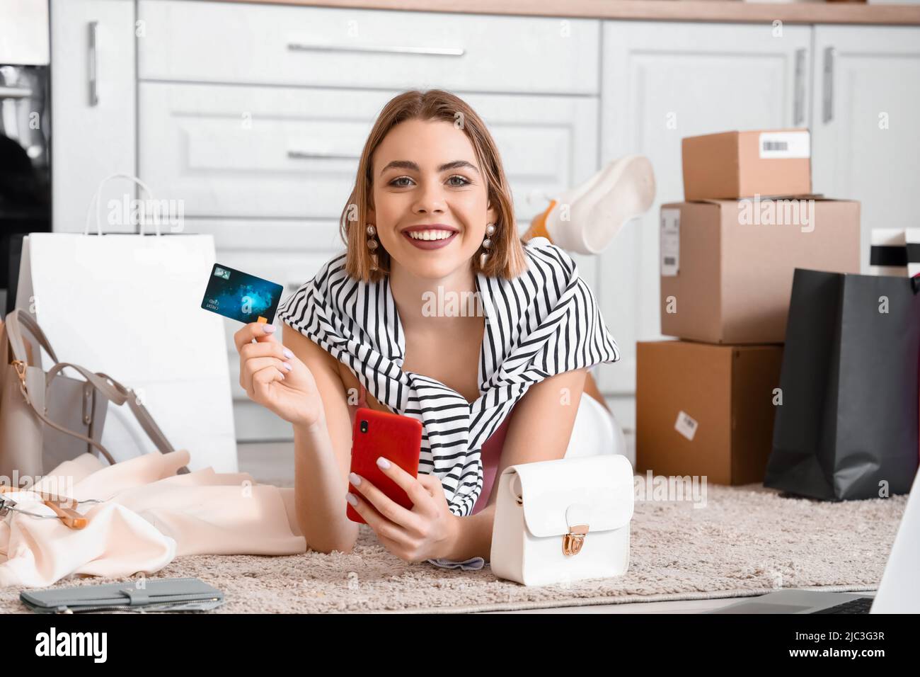 Young woman with credit card and mobile phone shopping online in ...