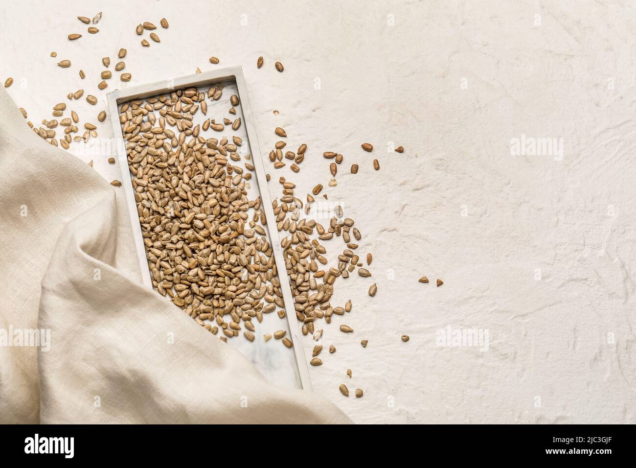 Board with peeled sunflower seeds and napkin on white background Stock ...