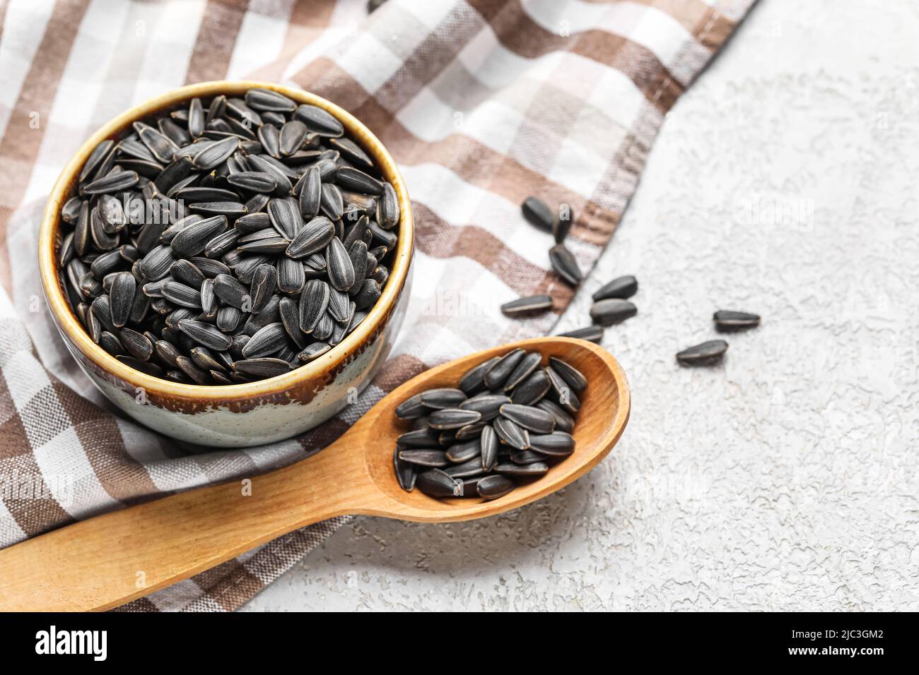 Bowl, spoon and napkin with black sunflower seeds on white background ...