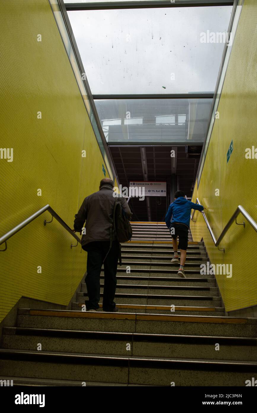 Two people walk up the steps to the platform at a train station Stock ...