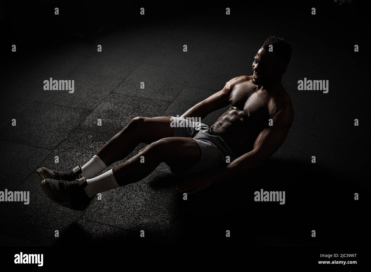Afro american man doing abdominal exercises in a dark studio Stock ...