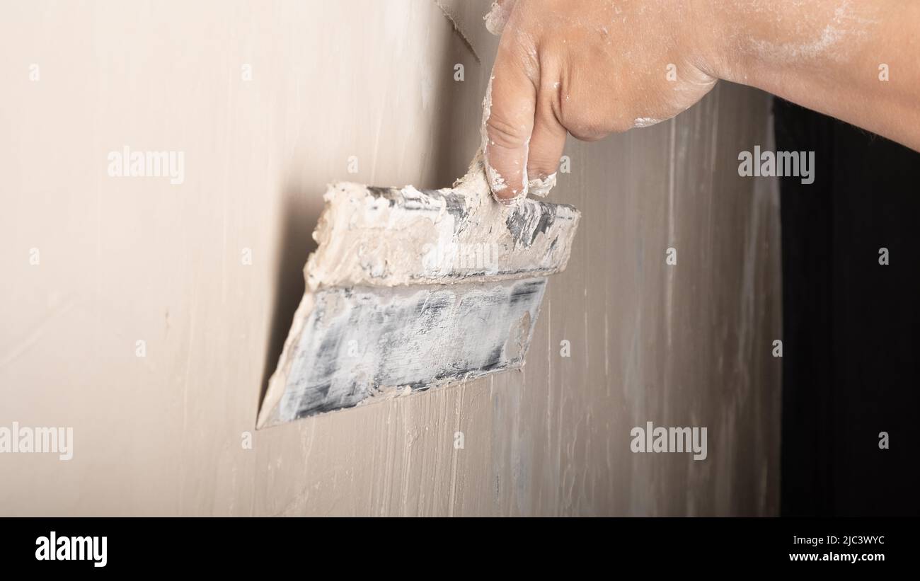 hand application of wall putty with a spatula closeup, plaster repair ...