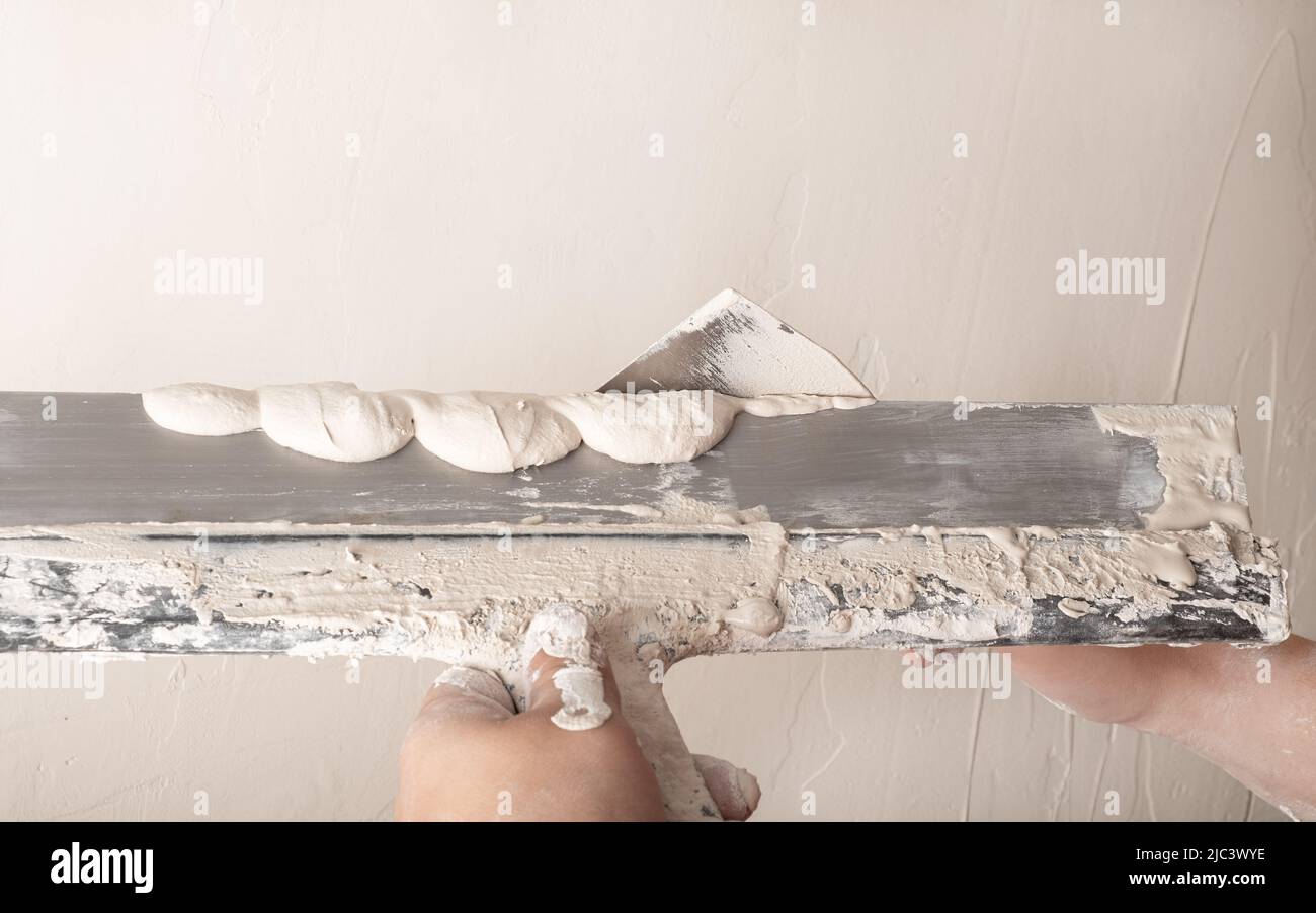 Builder plastering with a spatula and smoothing the wall with plaster ...