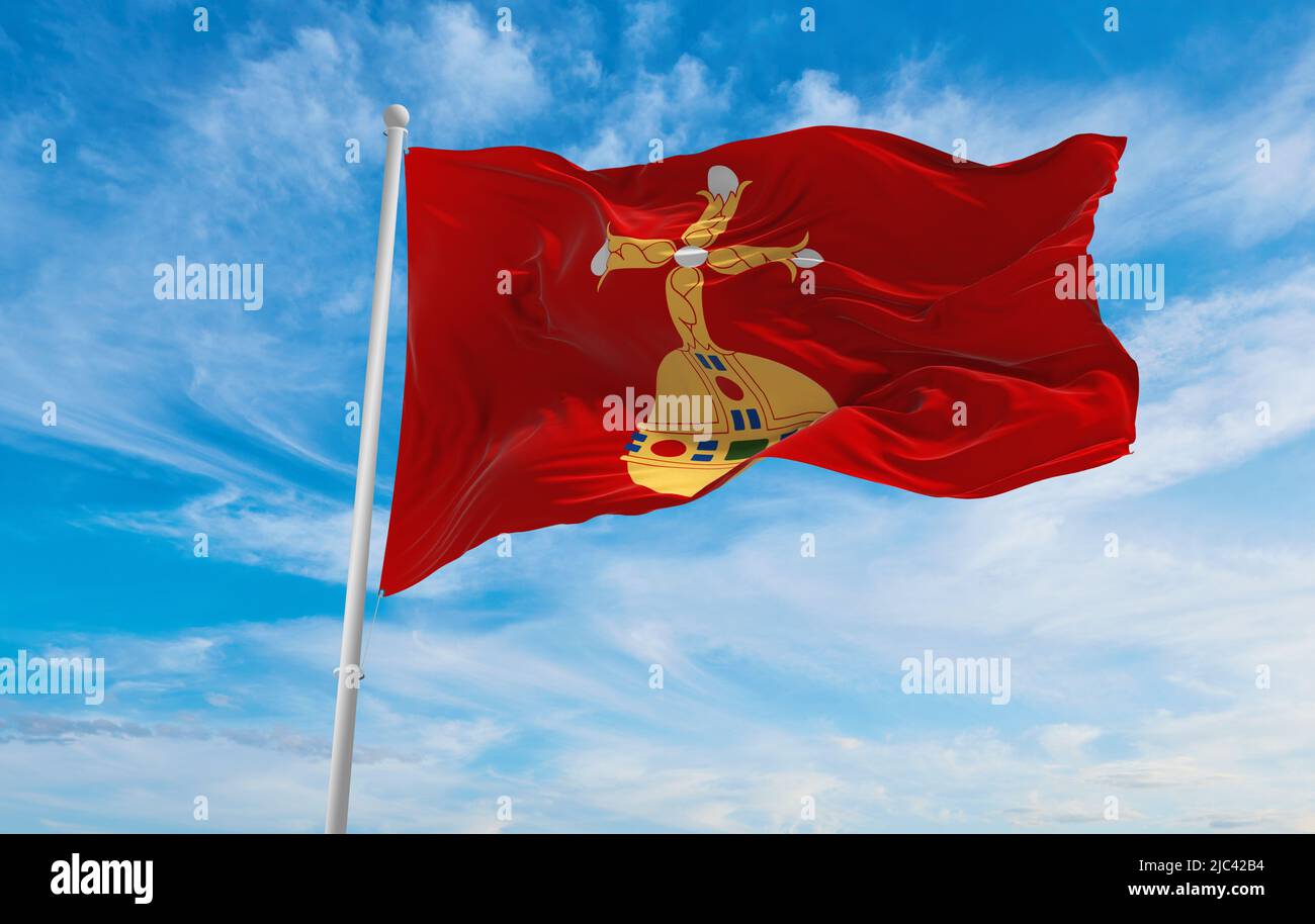 official flag of Uppsala , Sweden at cloudy sky background on sunset ...