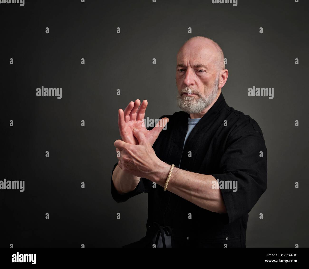 portrait of a senior man practicing reflexology therapy to his hand ...