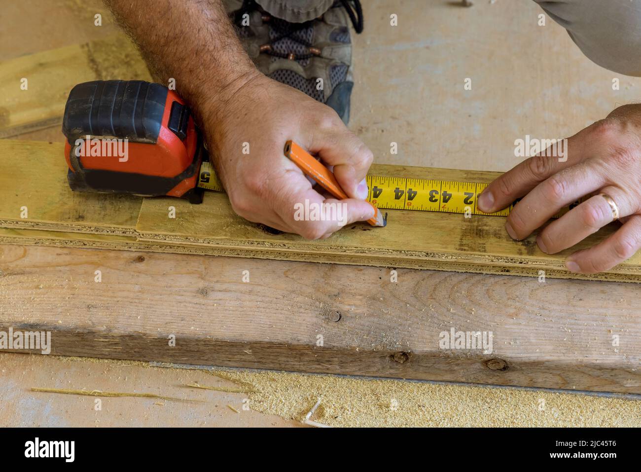 A man measures a piece of wood with tape measure Stock Photo - Alamy