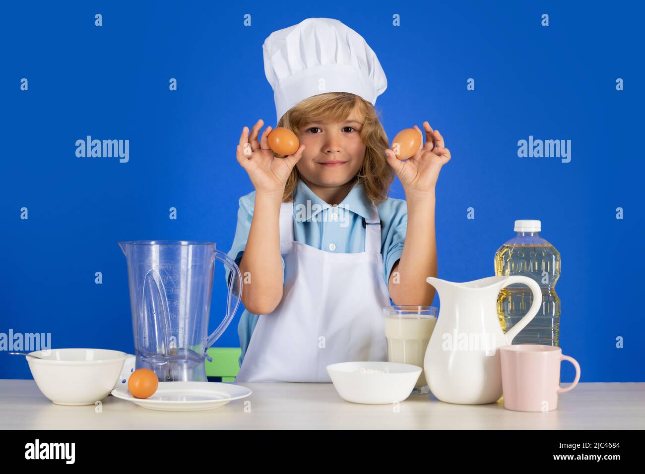 Cooking children. Chef kid boy hold eggs making fresh vegetables for ...