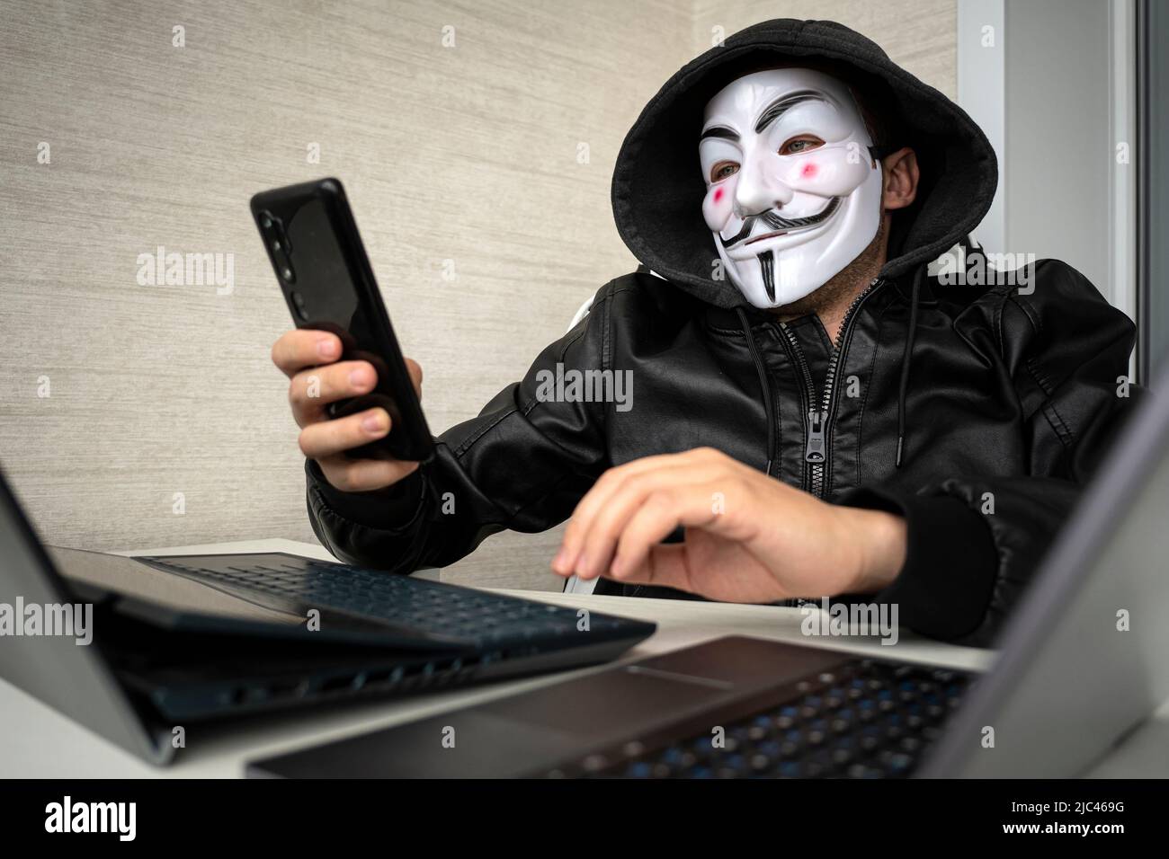 Hacker in the mask of anonymus using mobile phone Stock Photo - Alamy