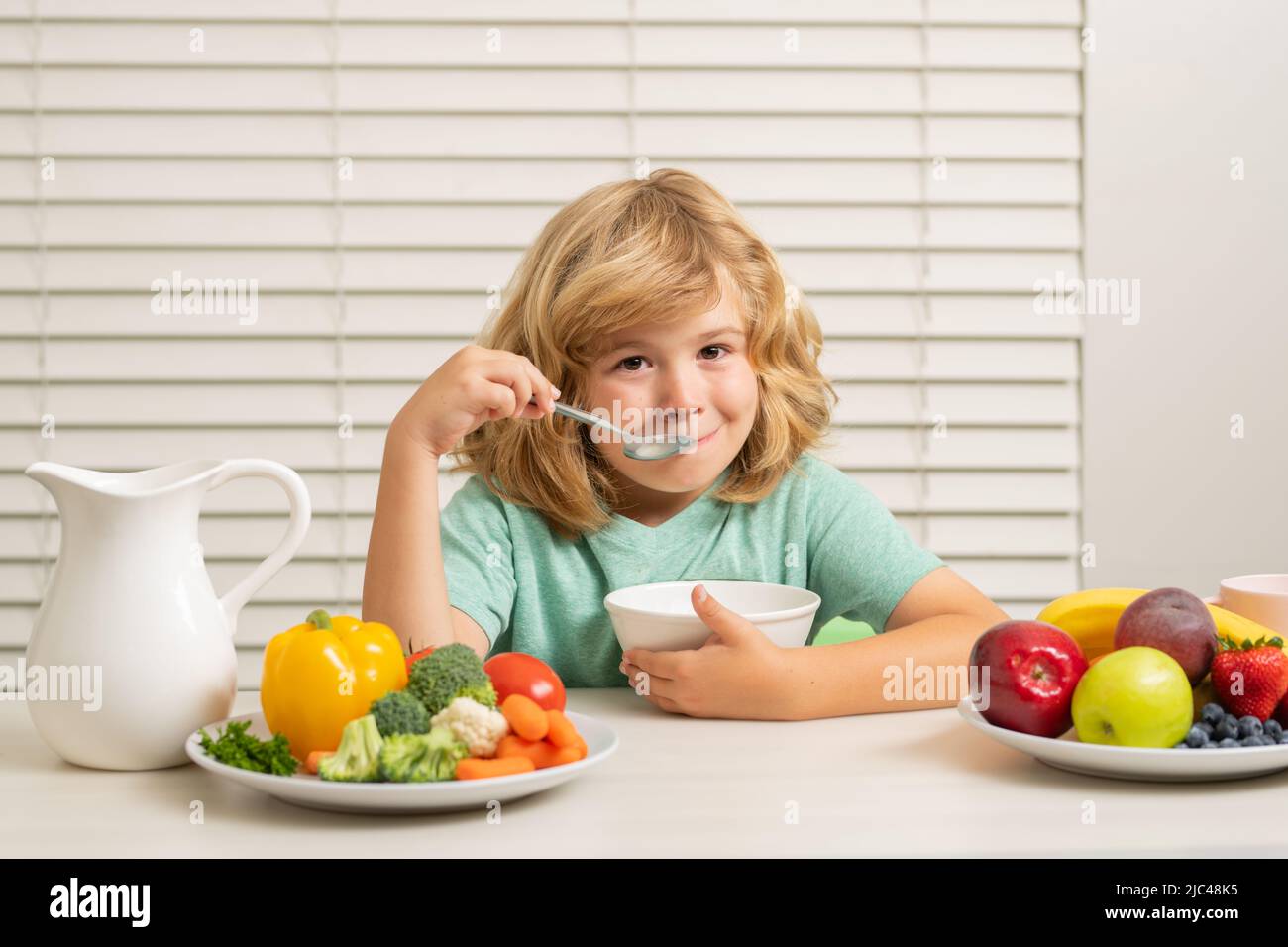 Kid boy eating healthy food vegetables. Breakfast with milk, fruits and ...