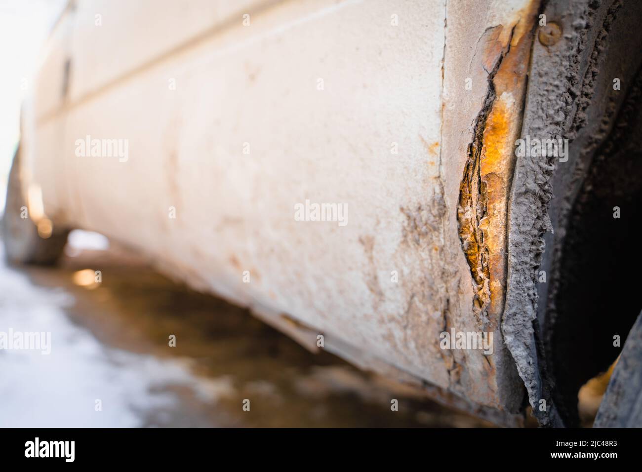 Rusted fender of a white car close-up. The effect of reagents in winter ...