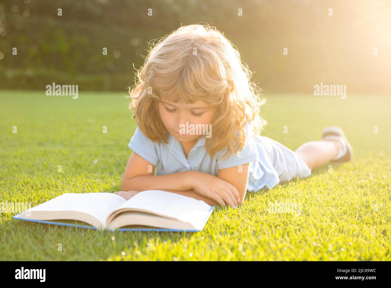 Smart clever Kids. Beautiful child boy book on grass background. Kids ...