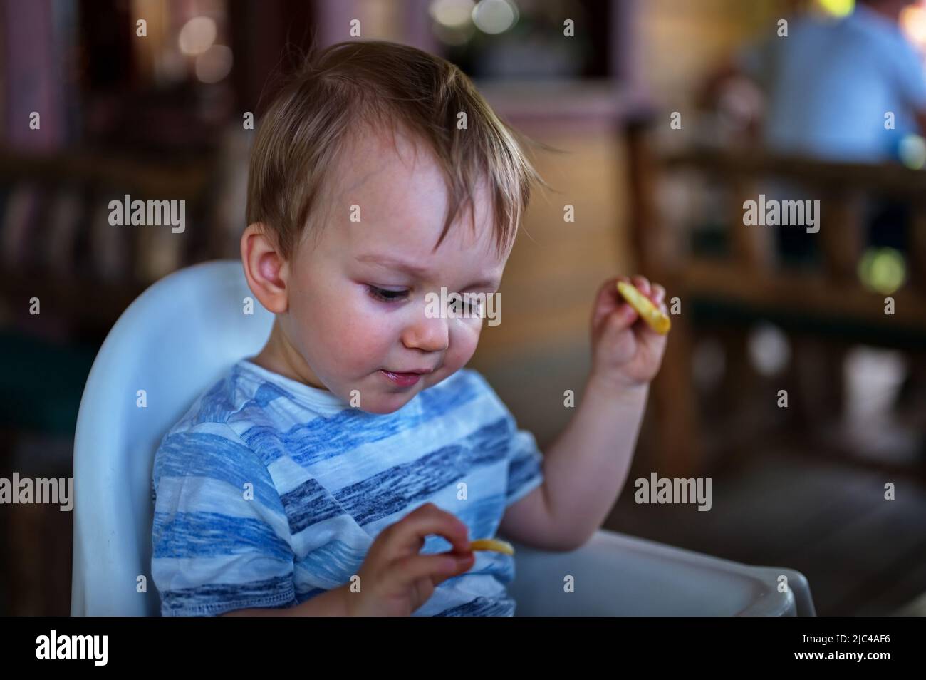 Portrait of cute boy eating potatoes with his fingers Stock Photo - Alamy