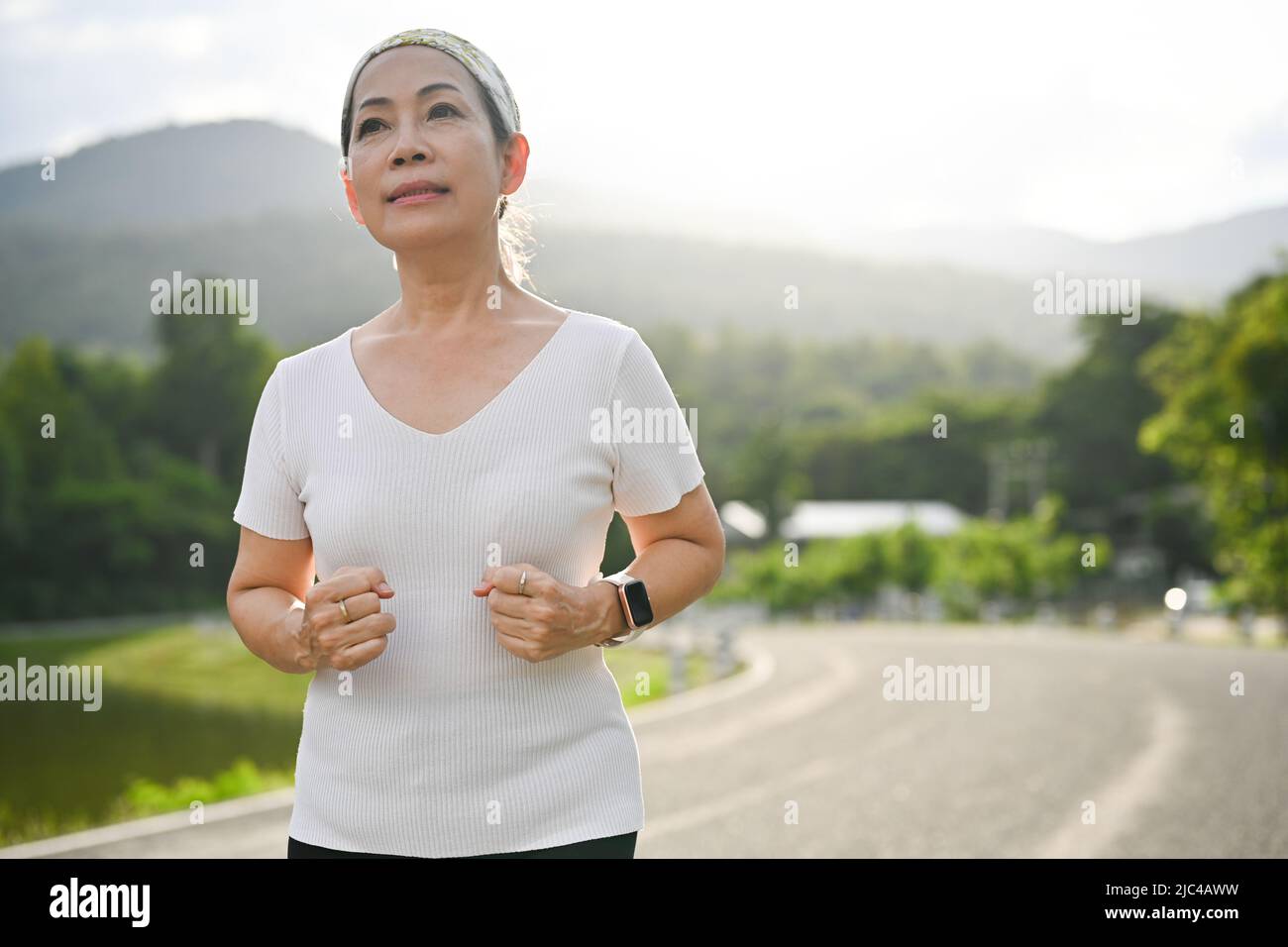 Beautiful Asian aged woman in a sportswear running or jogging on the ...