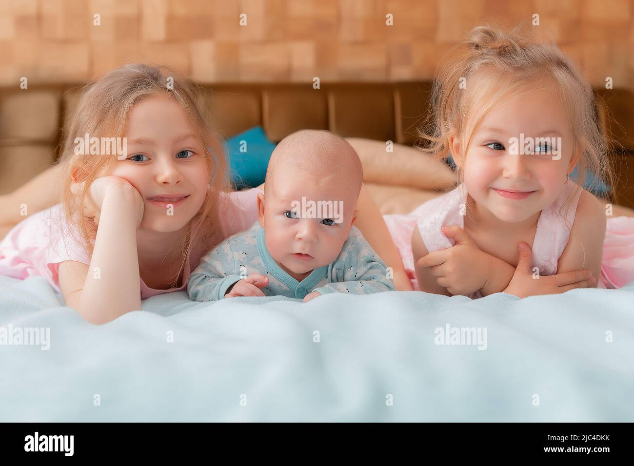 Portrait of a cute 3-month-old baby and two happy little sisters girls ...