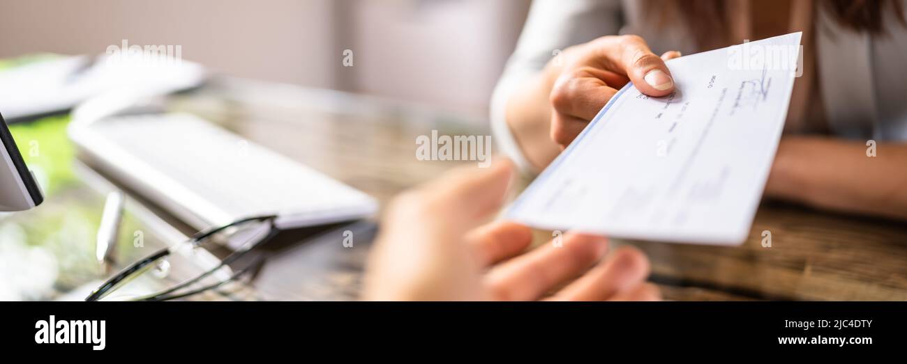 Close-up Of A Businesswoman Giving Cheque To Her Colleague At Workplace ...