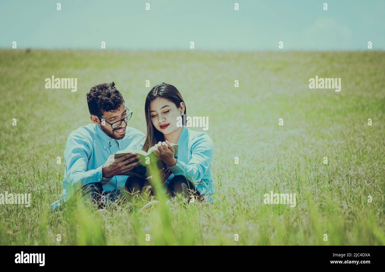 A couple sitting on the grass reading a book, Two people sitting on the ...