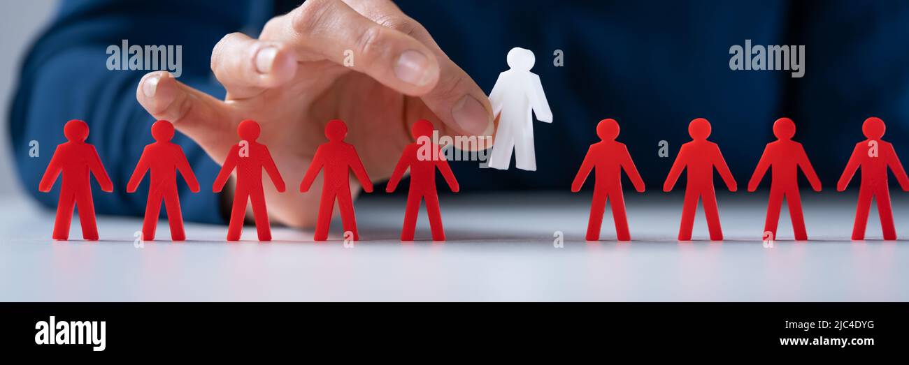 Businessperson's Hand Picking Red Human Figures Amongst Blue Figures In ...