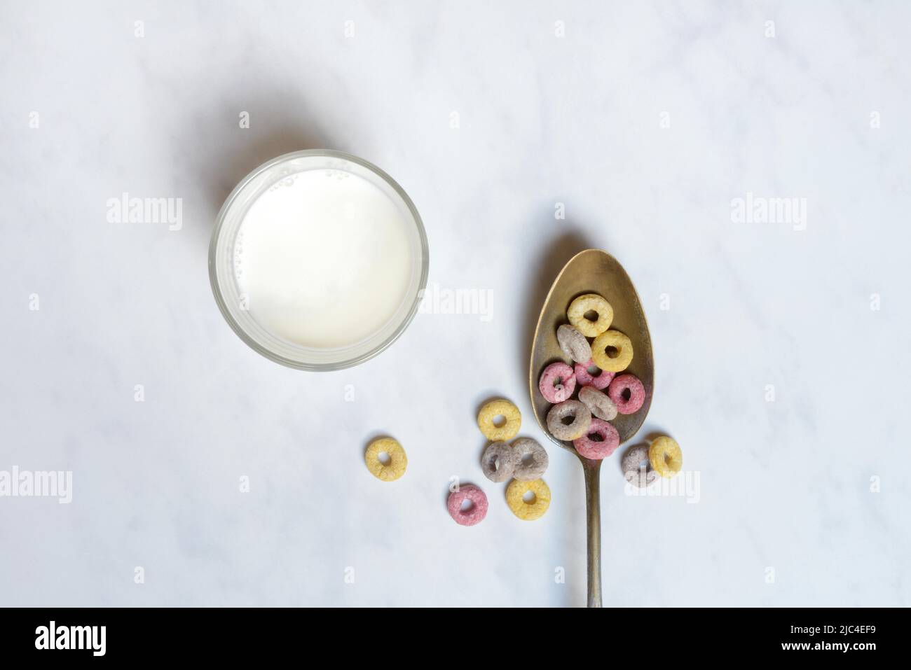 Fruit-flavoured cereal rings in spoon and glass of milk, children's ...