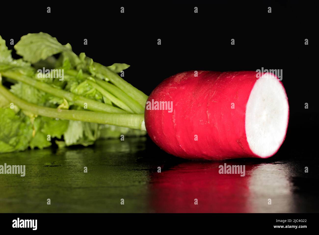 Cut fresh red radish with leaves, food photography in studio with black ...