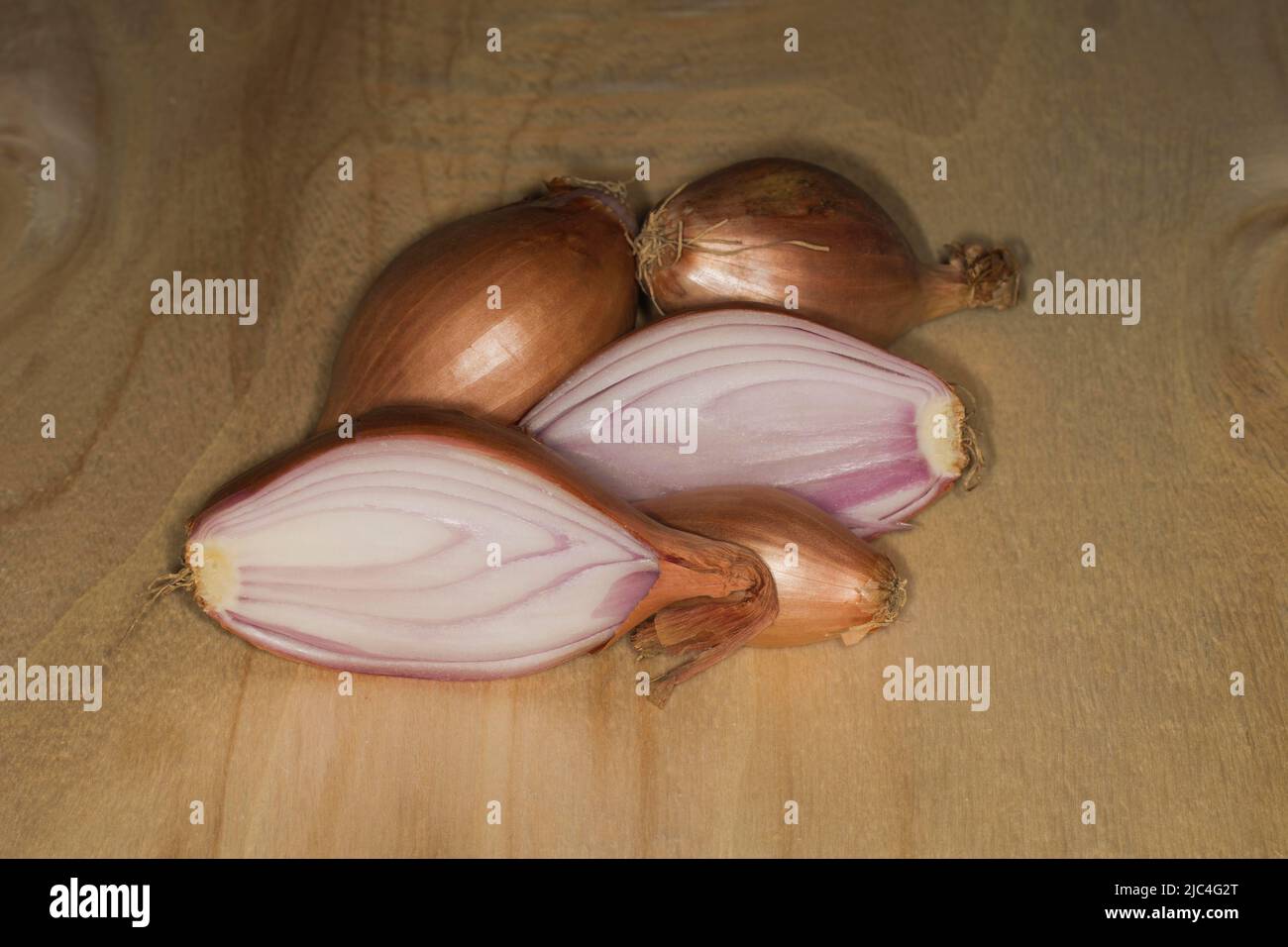 Half-baked common onion (Allium cepa var. aggregatum), on a wooden ...
