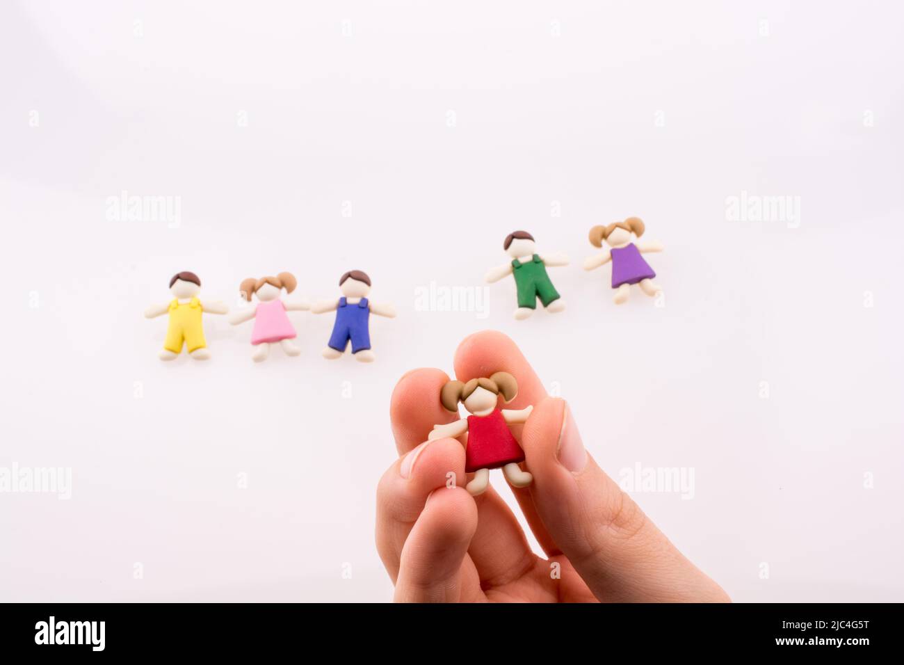 Hand holding colorful dressed children figure on a white background ...