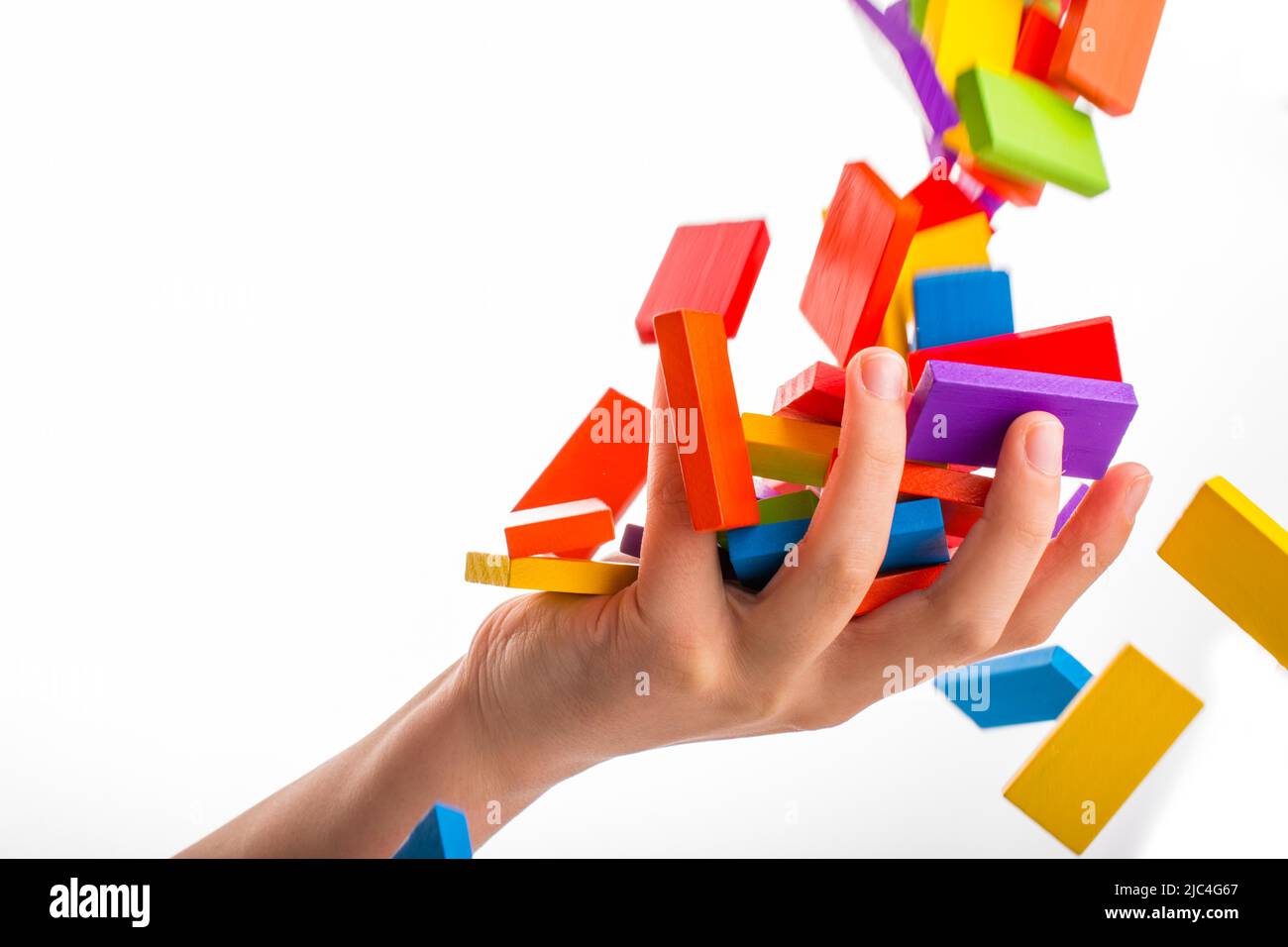 Falling colorful domino onto a hand Stock Photo - Alamy