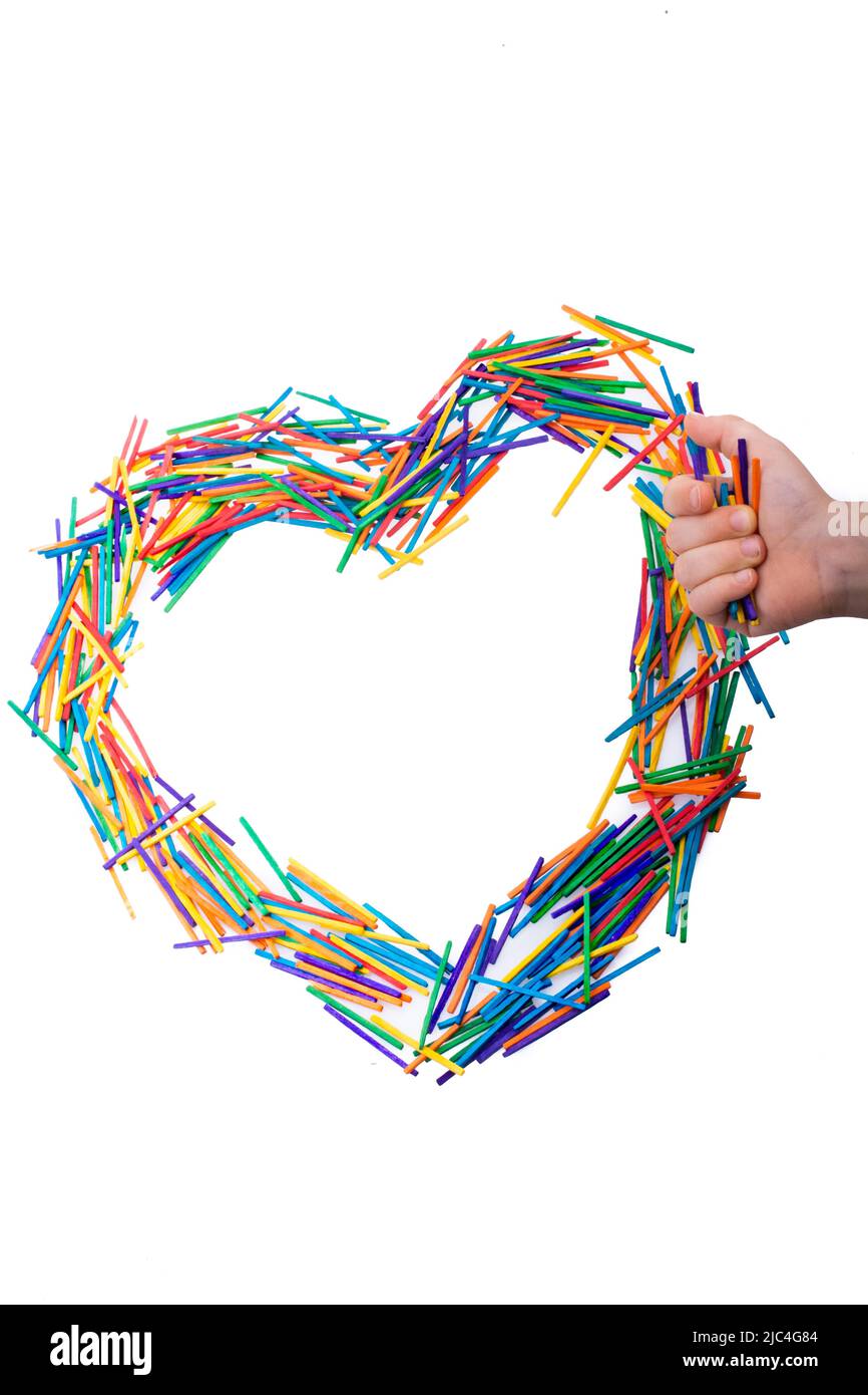 Coloured sticks formed heart shape by hand on white background Stock ...