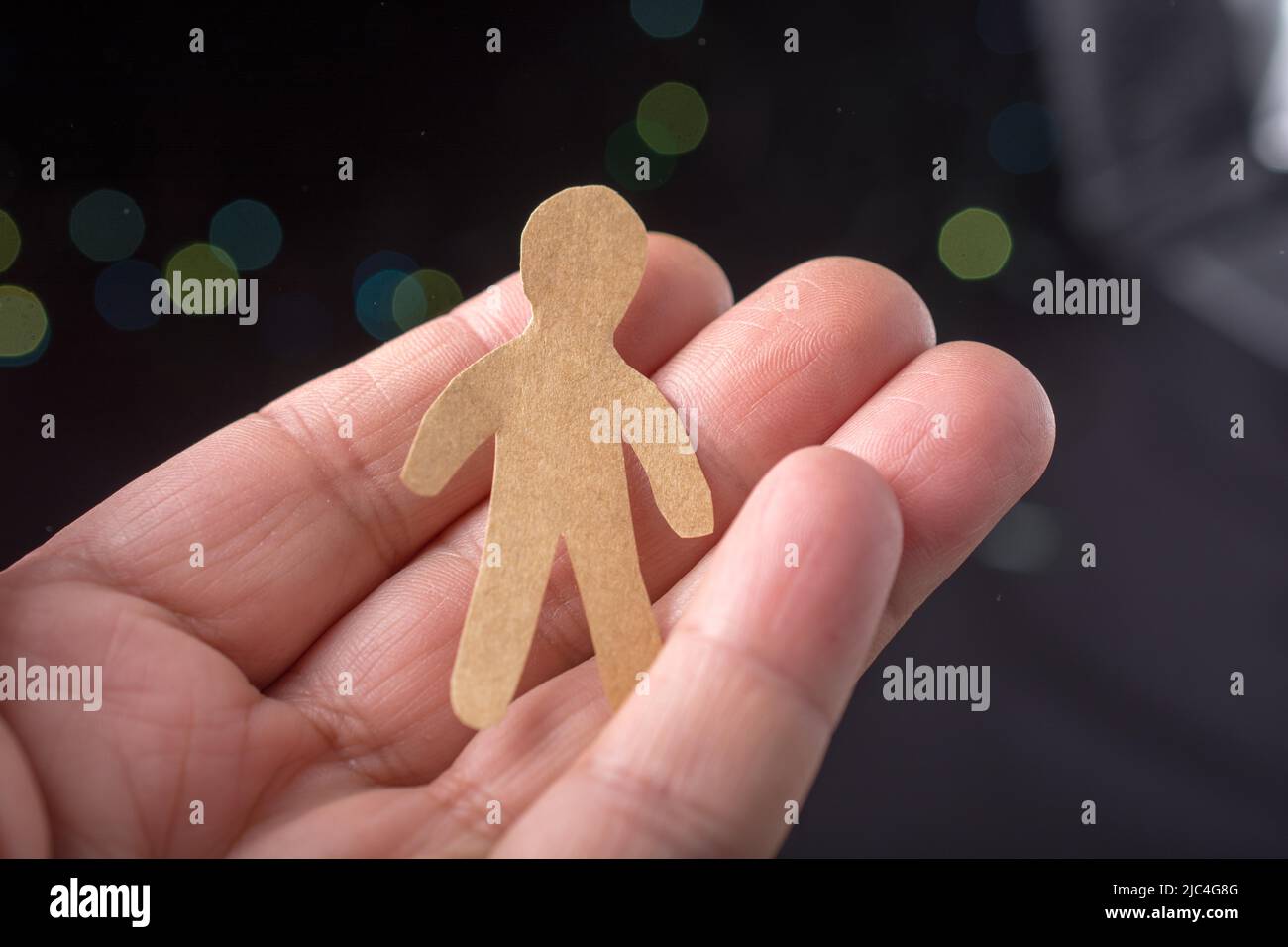 Paper man shape in hand on bokeh light background Stock Photo - Alamy